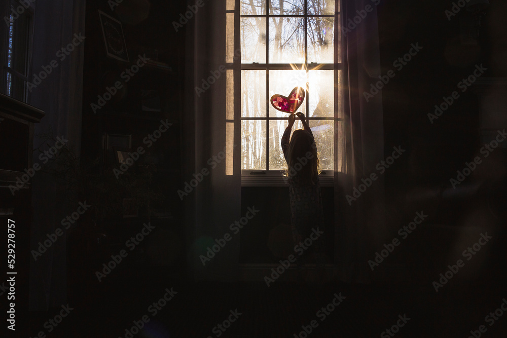 Rear view of playful girl making heart shape on window Stock Photo ...