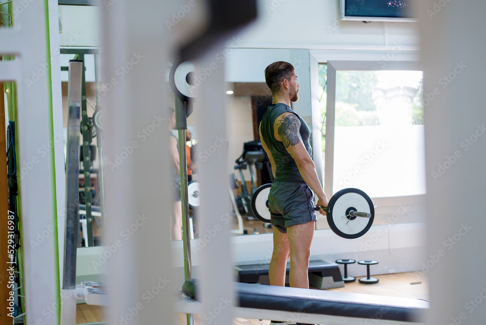 Side view of man lifting barbell while standing in gym Stock Photo ...