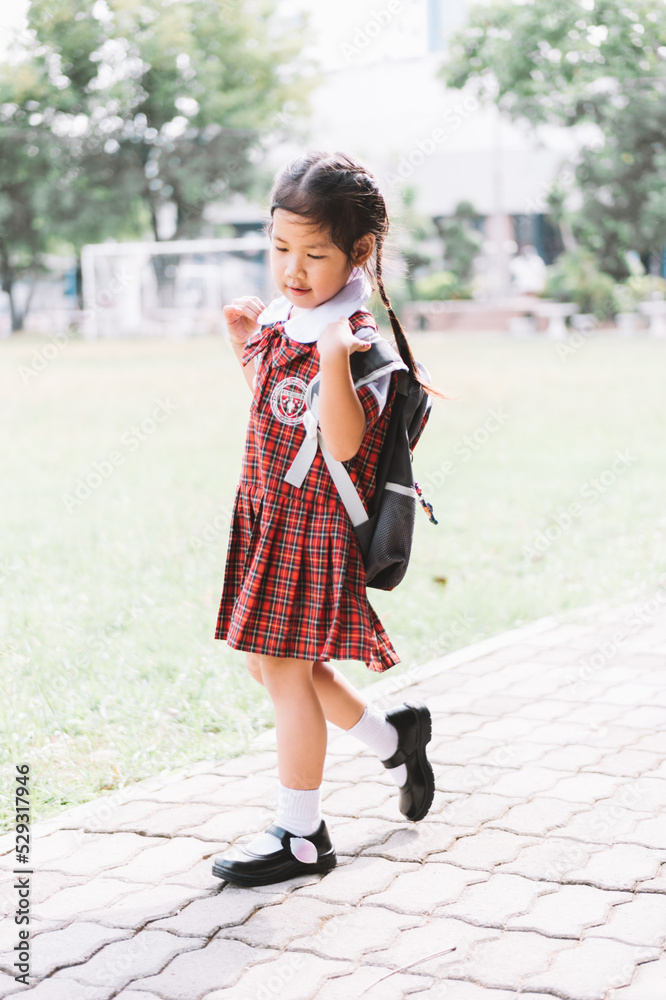 Girl in school uniform carrying backpack Stock Photo | Adobe Stock