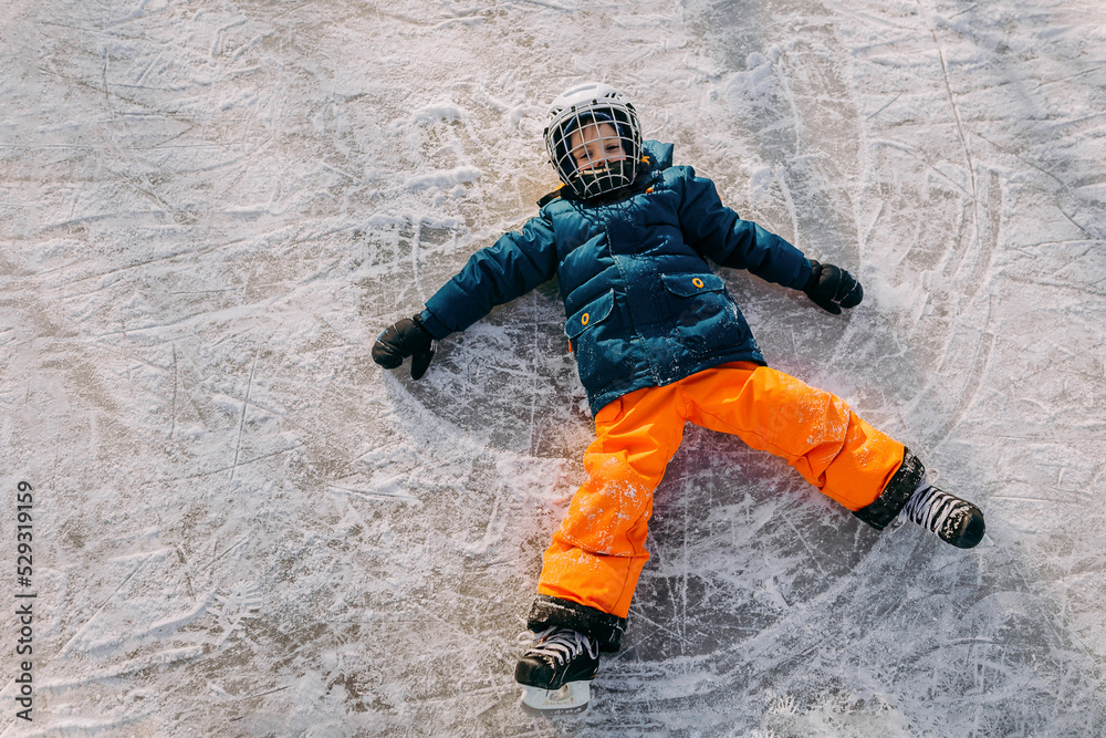 boy making angel on outdoor ice rink as he fell while skating Stock ...