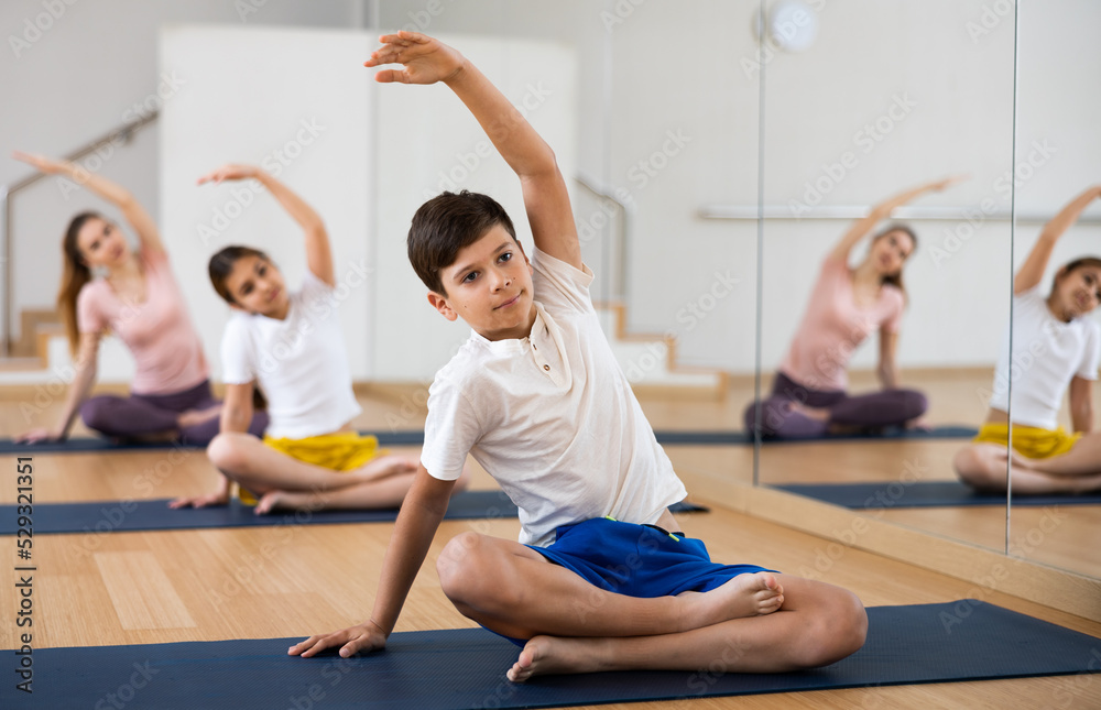 Stockfoto Smiling sporty tween boy doing stretching exercises while ...
