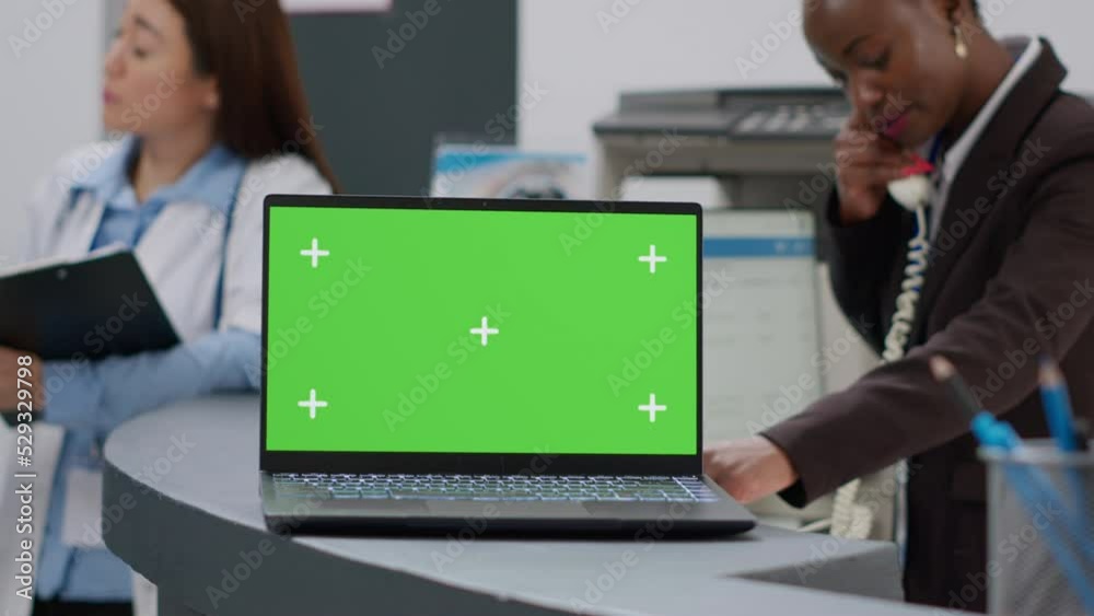 Laptop with greenscreen template on hospital reception counter. Medical ...