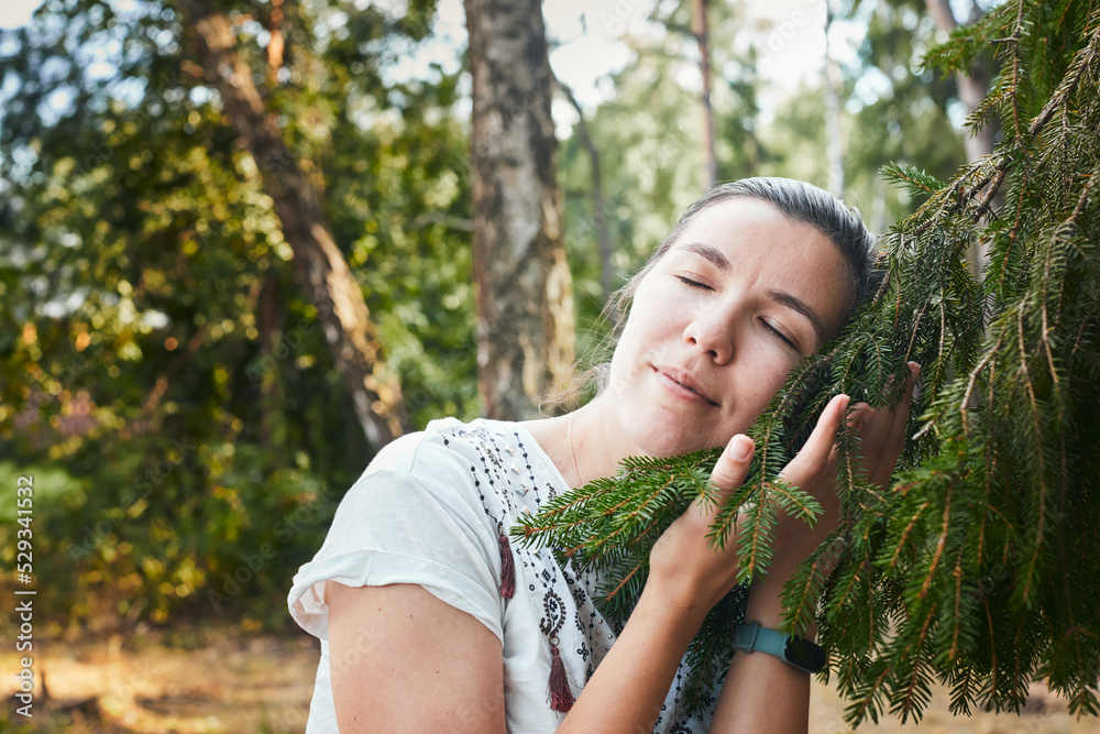 A woman embraces a coniferous tree in the forest. The concept of living ...