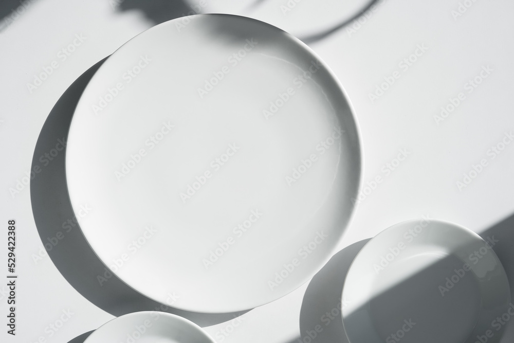 white plates of different shapes on a light background with beautiful ...