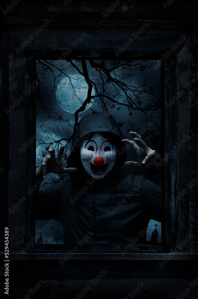 Scary evil clown wear jacket standing in old damaged wood window with ...