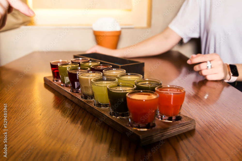 There is a wooden stand with shots on the bar counter. There are ...