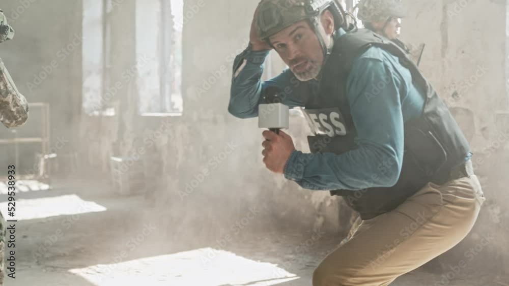 Male war correspondent speaking with male and female soldiers and ...