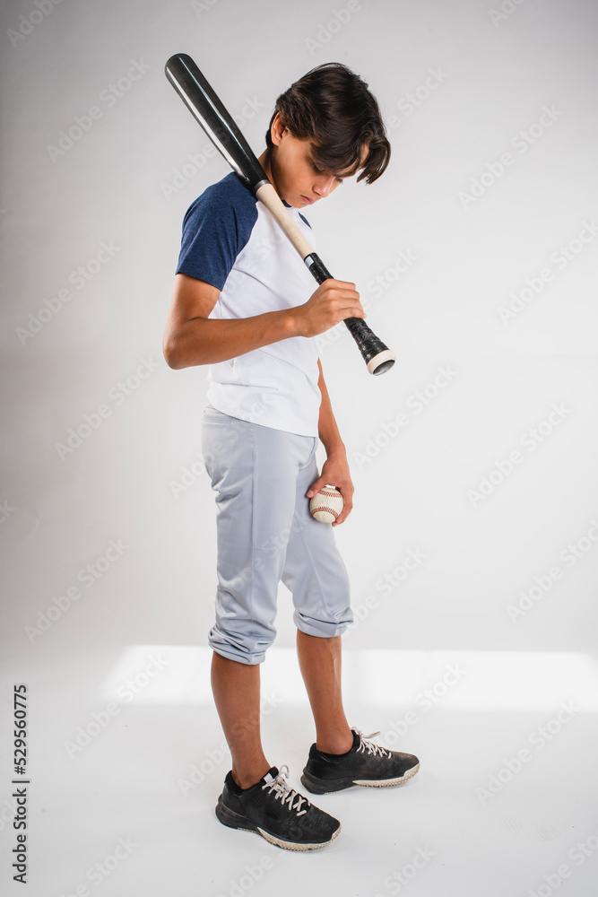 Teenage baseball player sadly looking down at the ground after losing a ...