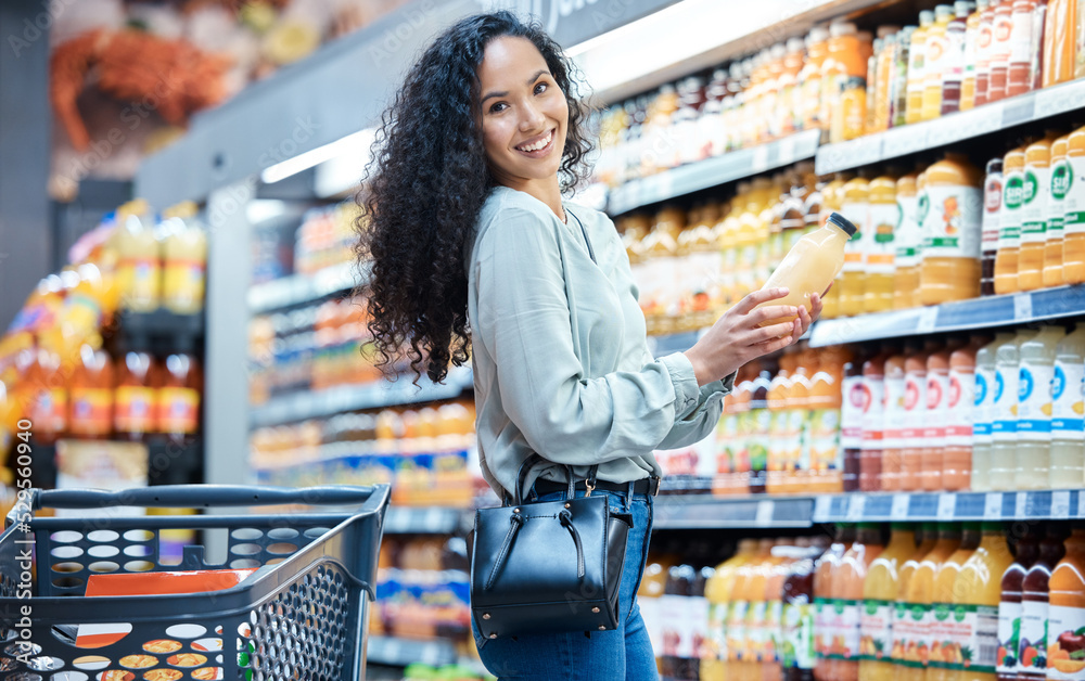 Portrait of a woman with juice while shopping in a grocery store with a ...