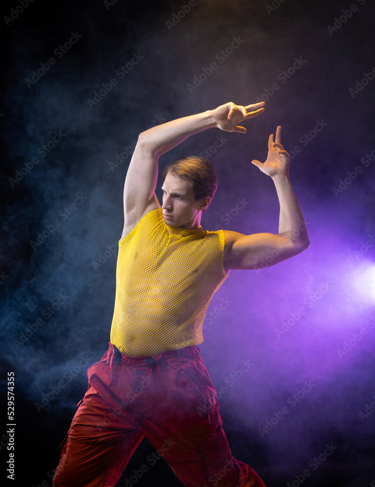 a young muscular man in a bright outfit poses in a pretentious pose ...