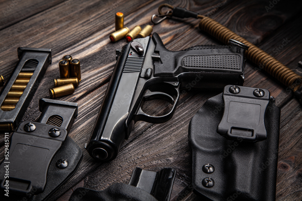 A modern black pistol and ammunition on dark metal back. Weapons for ...