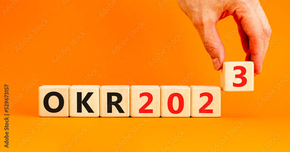 OKR, objectives and key results symbol. Businessman turns cubes with words OKR 2022 and OKR 2023 ...