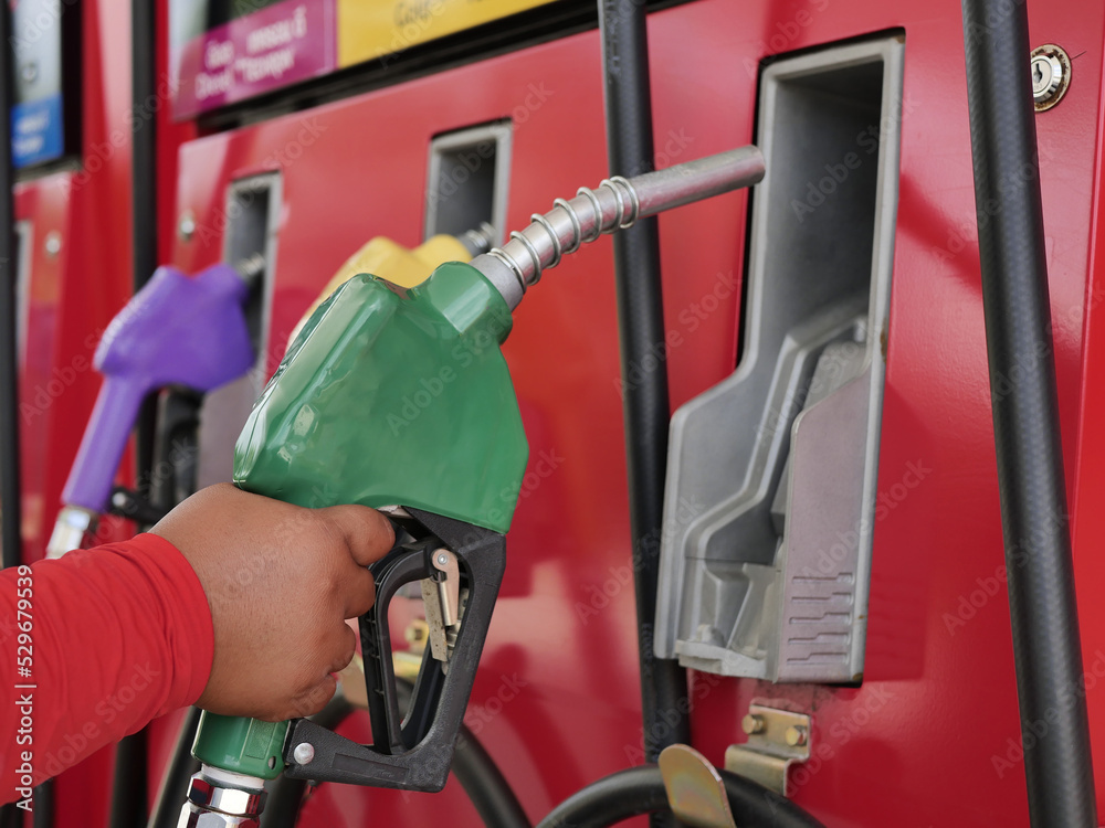 man hand holding a green gas nozzle. A man's hand is pulling the fuel ...