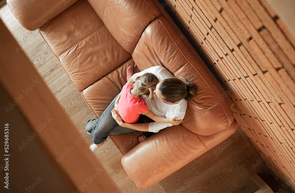 Top view of single mother sitting on the couch at home holding her ...
