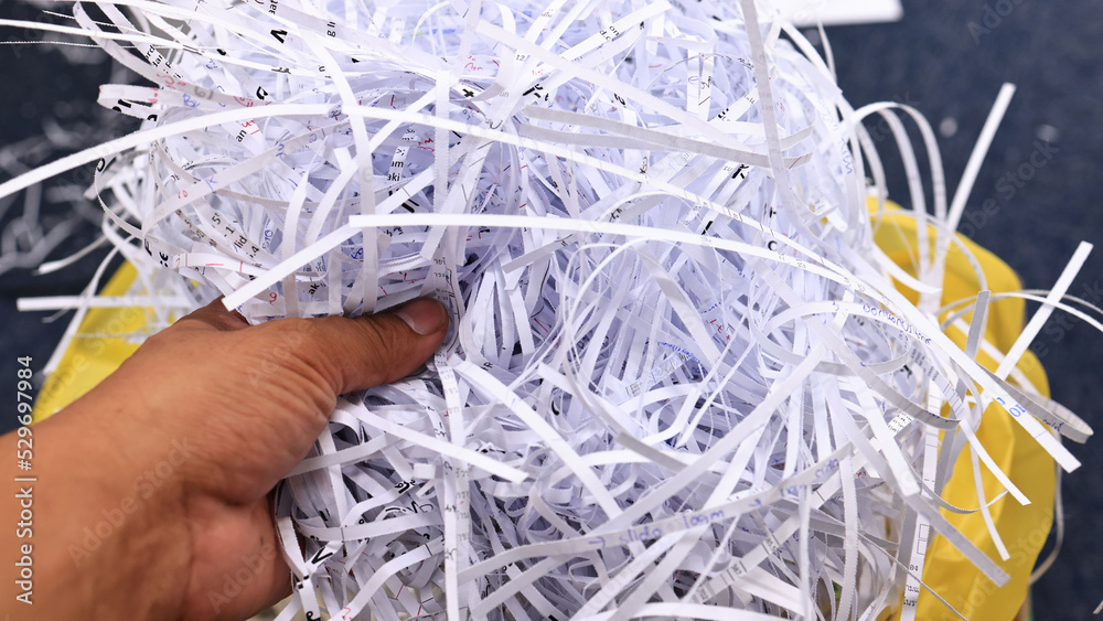 Close up hand pick up the reuse paper from paper shredder machine ...