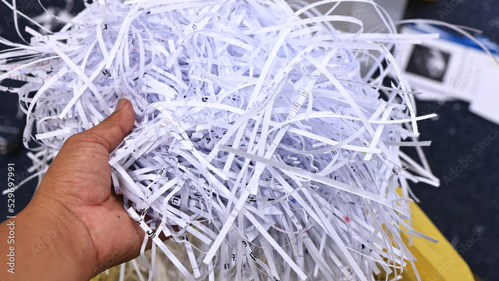 Close up hand pick up the reuse paper from paper shredder machine ...