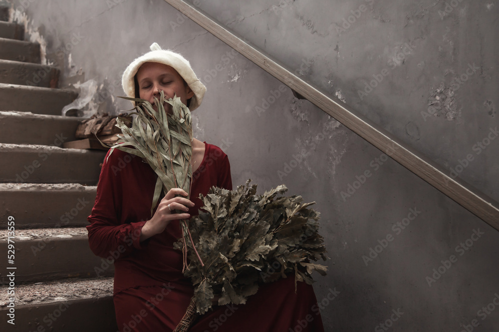 Woman in traditional dress with bath brooms in traditional steam sauna ...