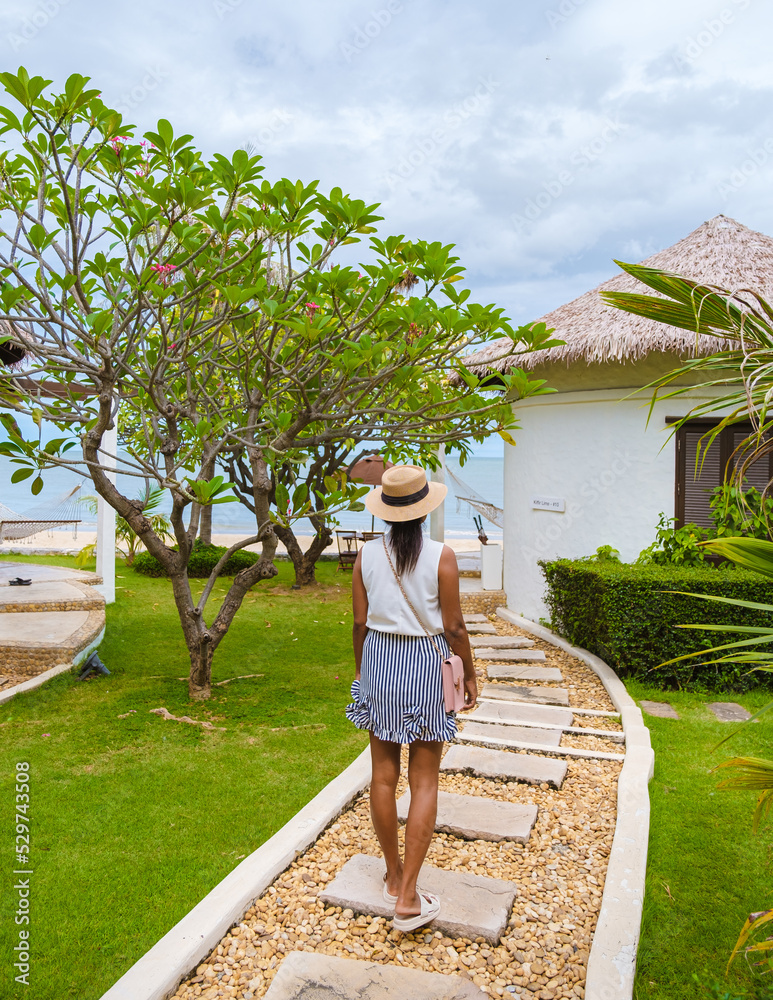 Women in luxury villas walk to look out over the ocean and beach on a ...