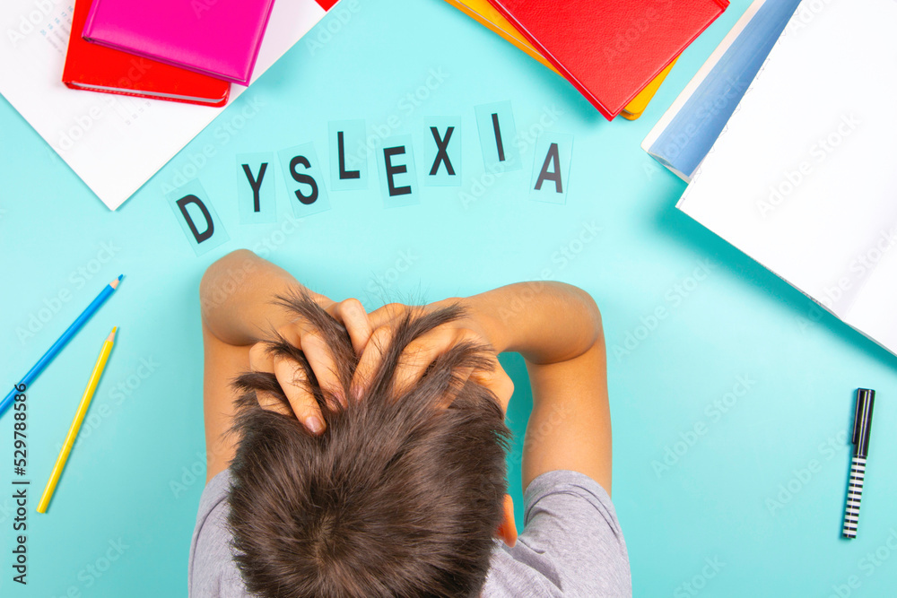 Sad tired frustrated teenage boy sitting at table with many books and ...