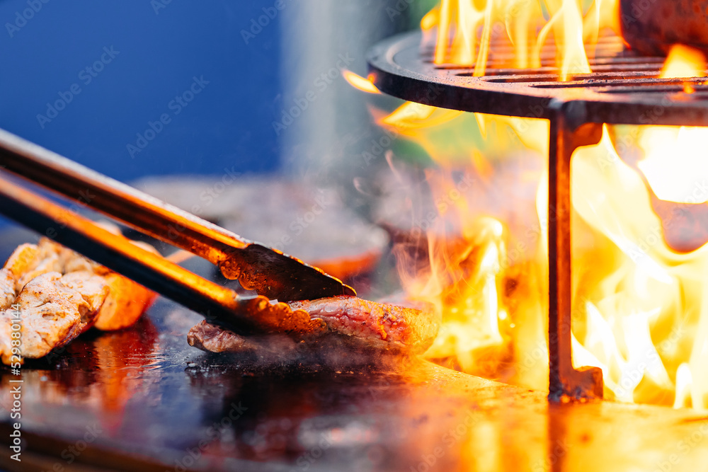 Street food concept. Chef cook prepares Beef steak is fried on open ...