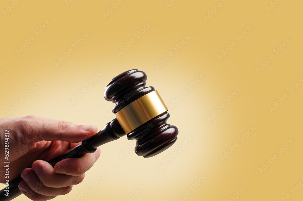 Wooden judge's gavel in a man's hand on a beige background. Symbol of ...