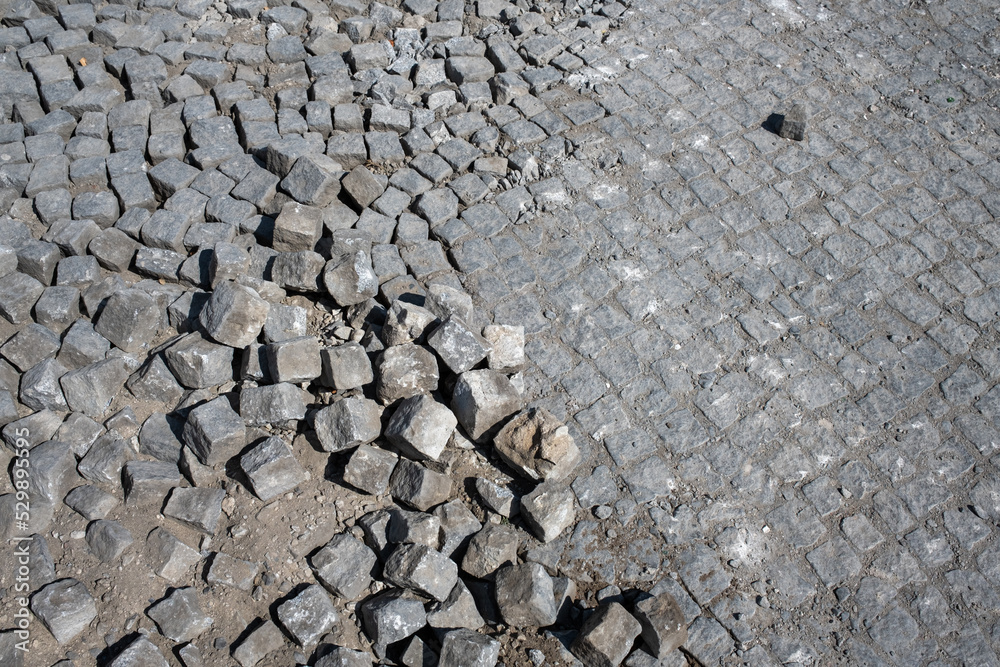 damaged road paved with setts. Loose paving stones in a cobblestone ...