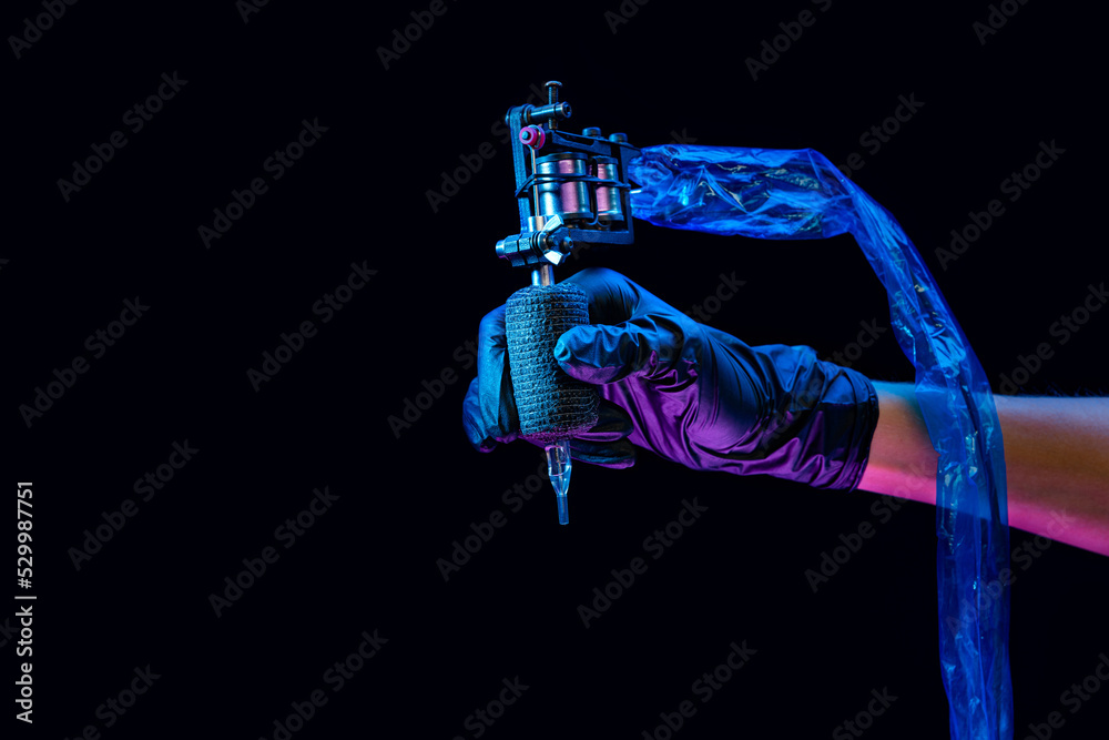 Closeup of tattooer master's hand in black glove holding machine for ...
