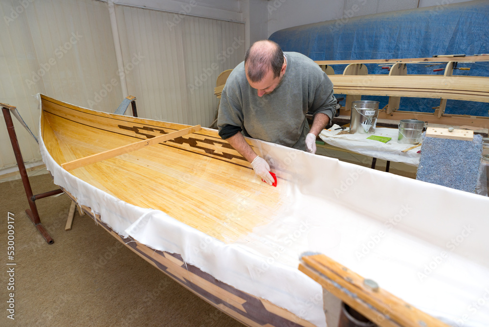 Young carpenter making wooden boat of his own design in his workshop ...