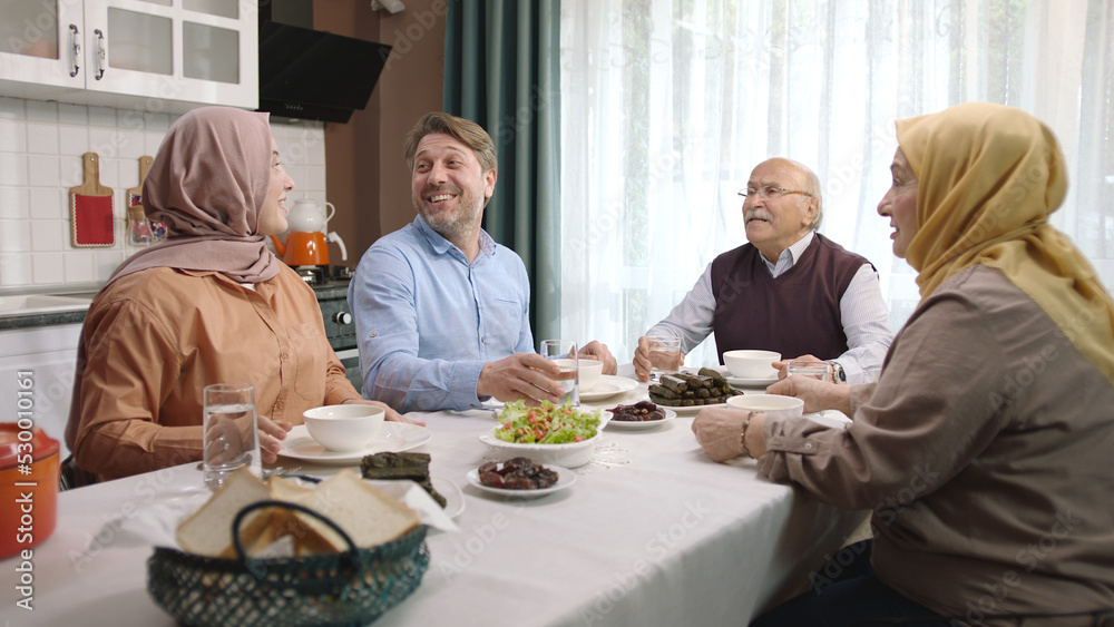 Happy Muslim family having iftar dinner together in the kitchen. A ...