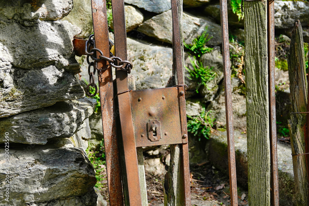 Ein altes, rostiges Tor im closeup mit Blick auf das Schloss und den ...
