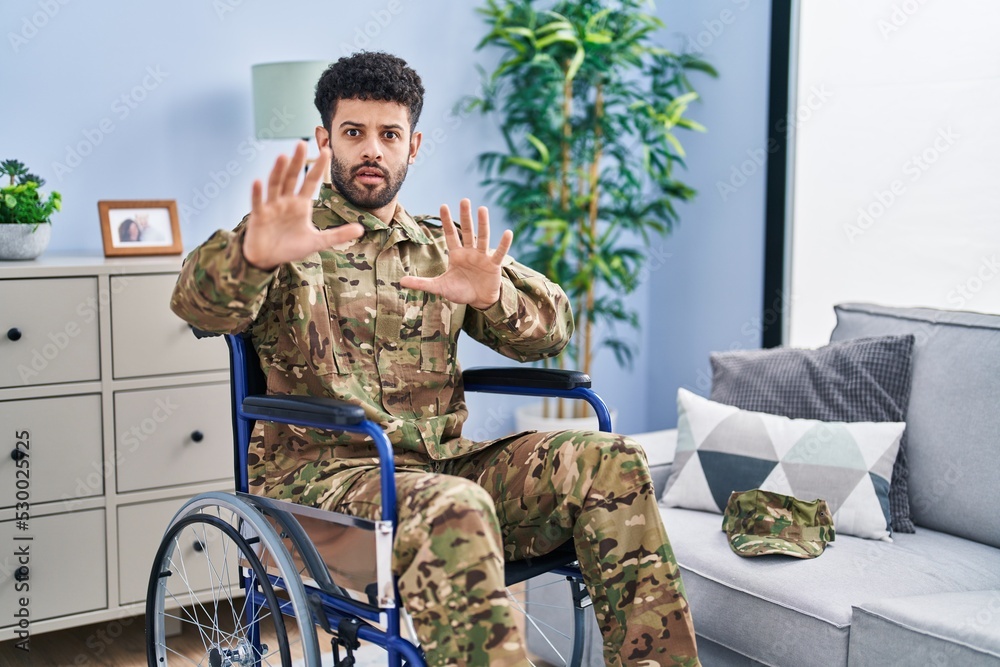 Arab man wearing camouflage army uniform sitting on wheelchair afraid ...
