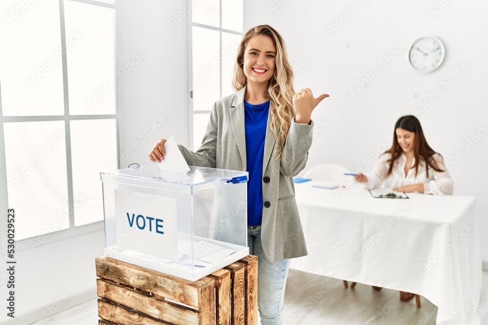 Young blonde woman voting putting envelop in ballot box smiling happy ...