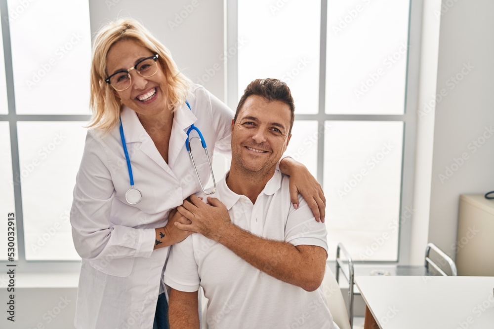 Middle age man and woman doctor and patient hugging each other having ...