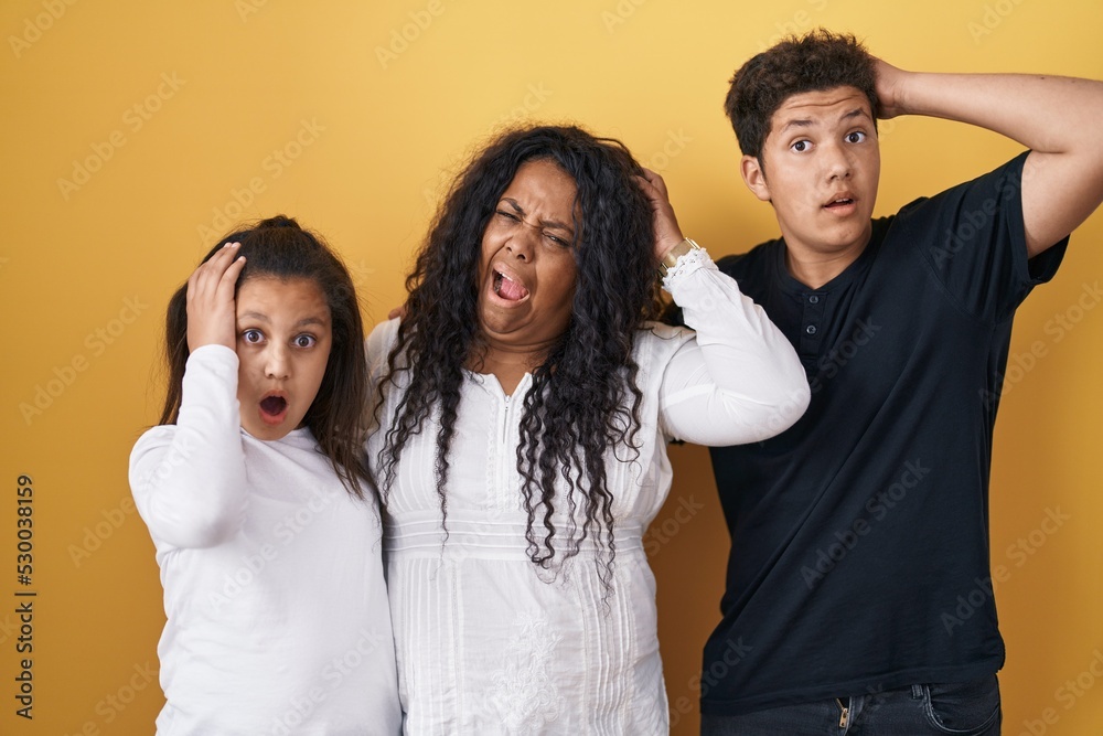 Family of mother, daughter and son standing over yellow background ...