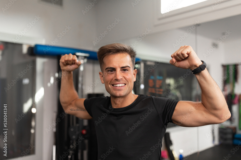 A male coach showing off her muscles with her arms raised as a symbol ...
