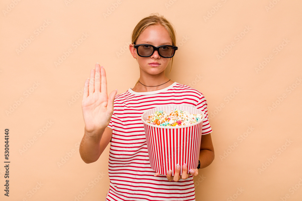 Little caucasian girl eating popcorn isolated on beige background ...
