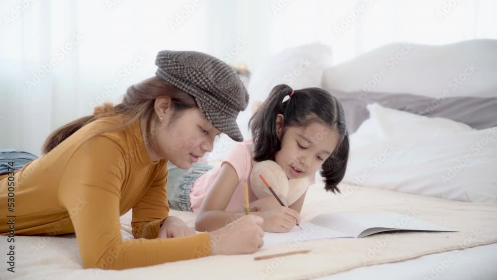 Sibling drawing in paper together on bed, elder sister and adorable ...