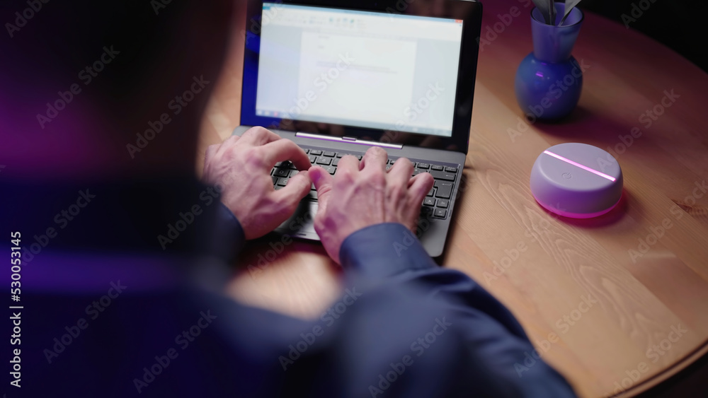 Foto de Over shoulder of person typing on laptop with a base light ...