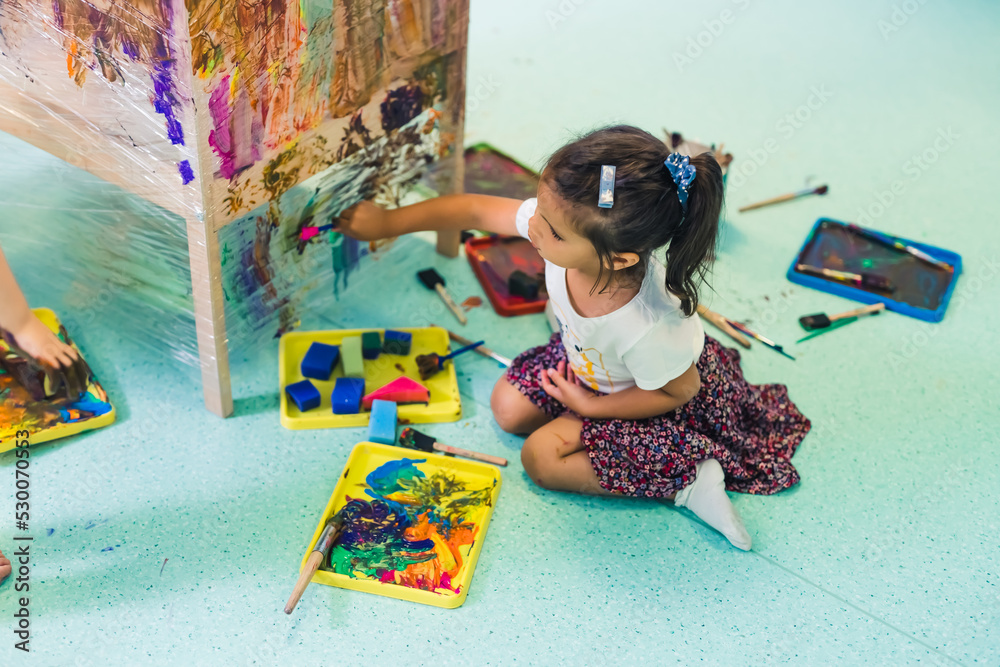 Cling film painting. Little girl toddler painting with a sponge and ...