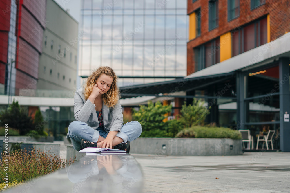 Young beautiful student with curly hair studying at free time, outside ...