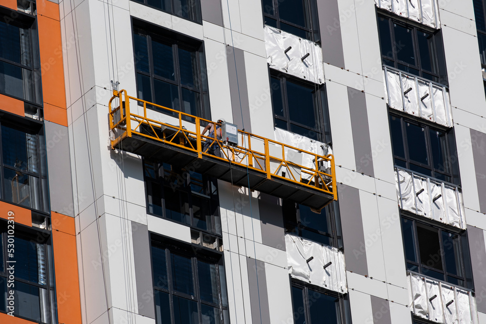 Builders perform work at height in the cradle. The workflow for the ...