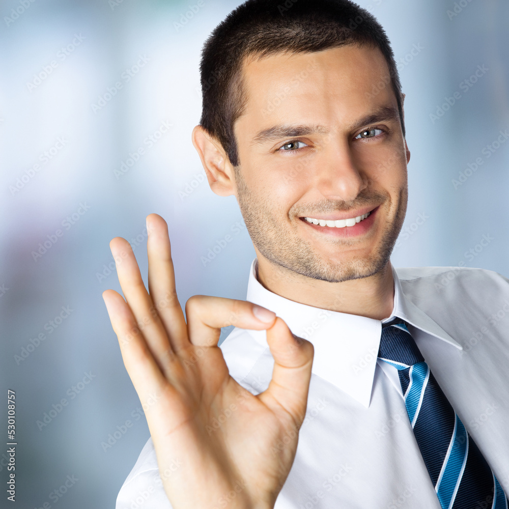 Portrait of smiling businessman in white shirt and tie, showing okay ...