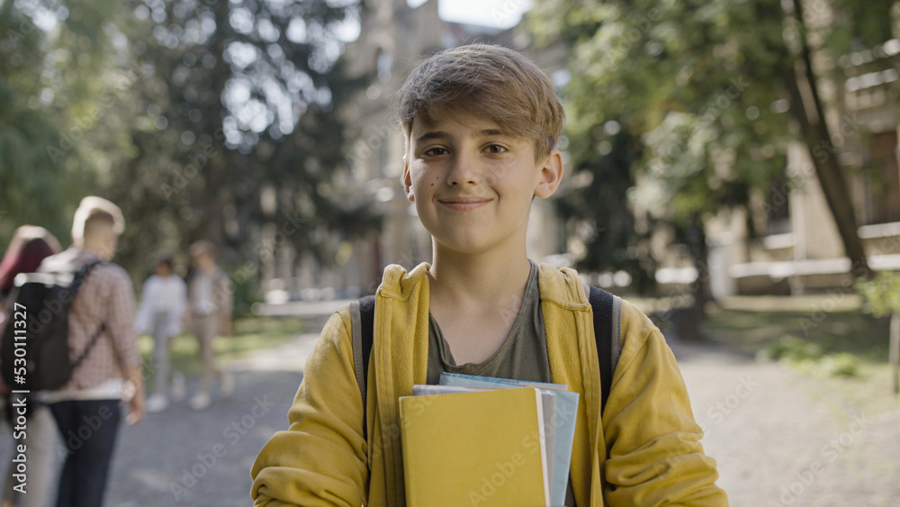 Nice middle school boy smiling on camera, holding books, ready for ...
