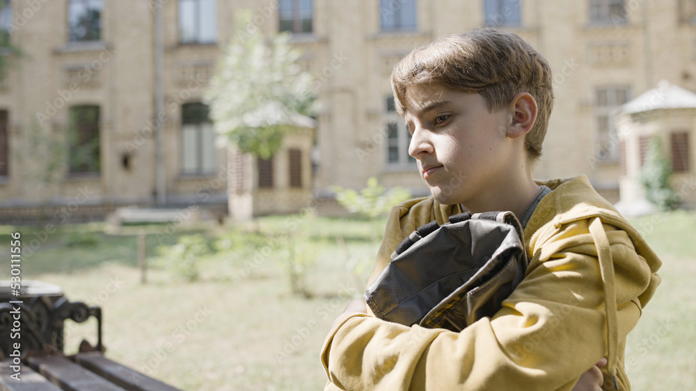 Unhappy school boy sitting alone near school, no friends, bullying ...