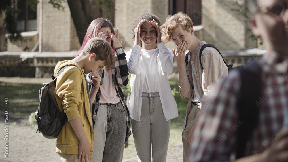 Group of school children gossiping and laughing at insecure classmate ...