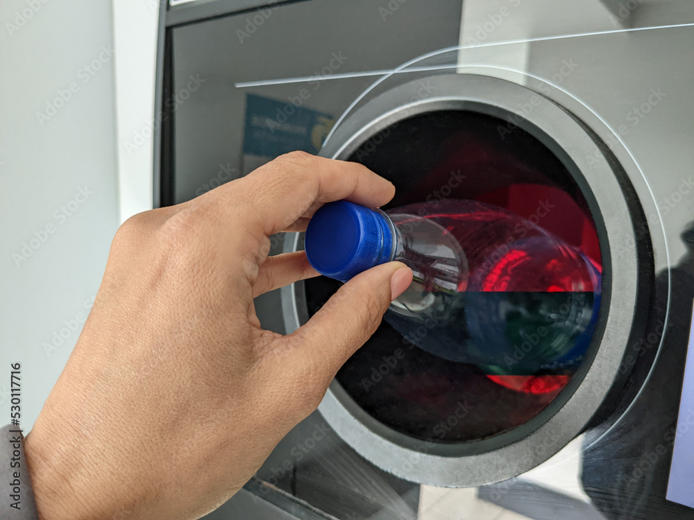 Reverse vending machine. Woman hand put empty plastic bottle in the ...