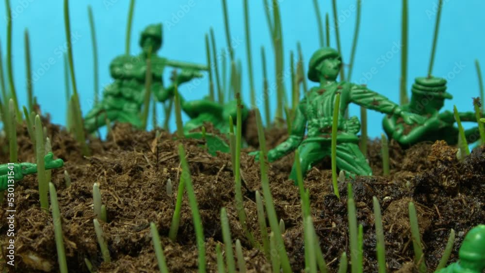 Green plastic toy soldiers are standing on the ground through which ...