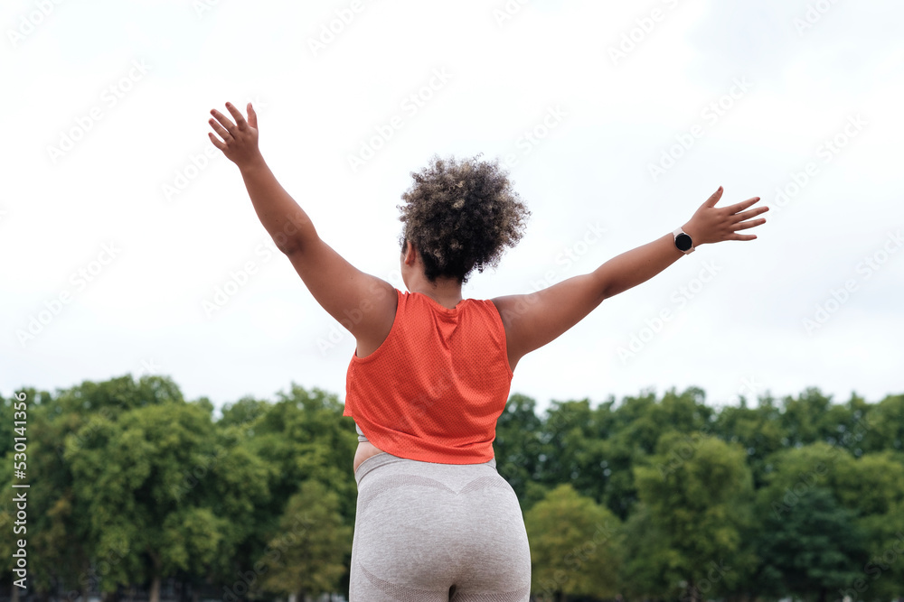 Back view of curvy young woman opening her arms in triumph. Overcoming ...