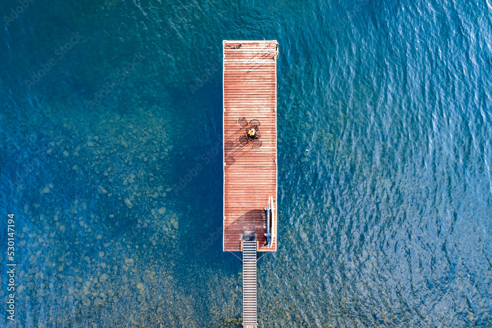 Poster Wooden dock on a lake overhead aerial with clear blue water ...