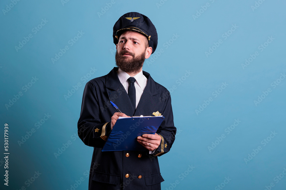 Airplane captain holding clipboard, filling documents, concentrated ...
